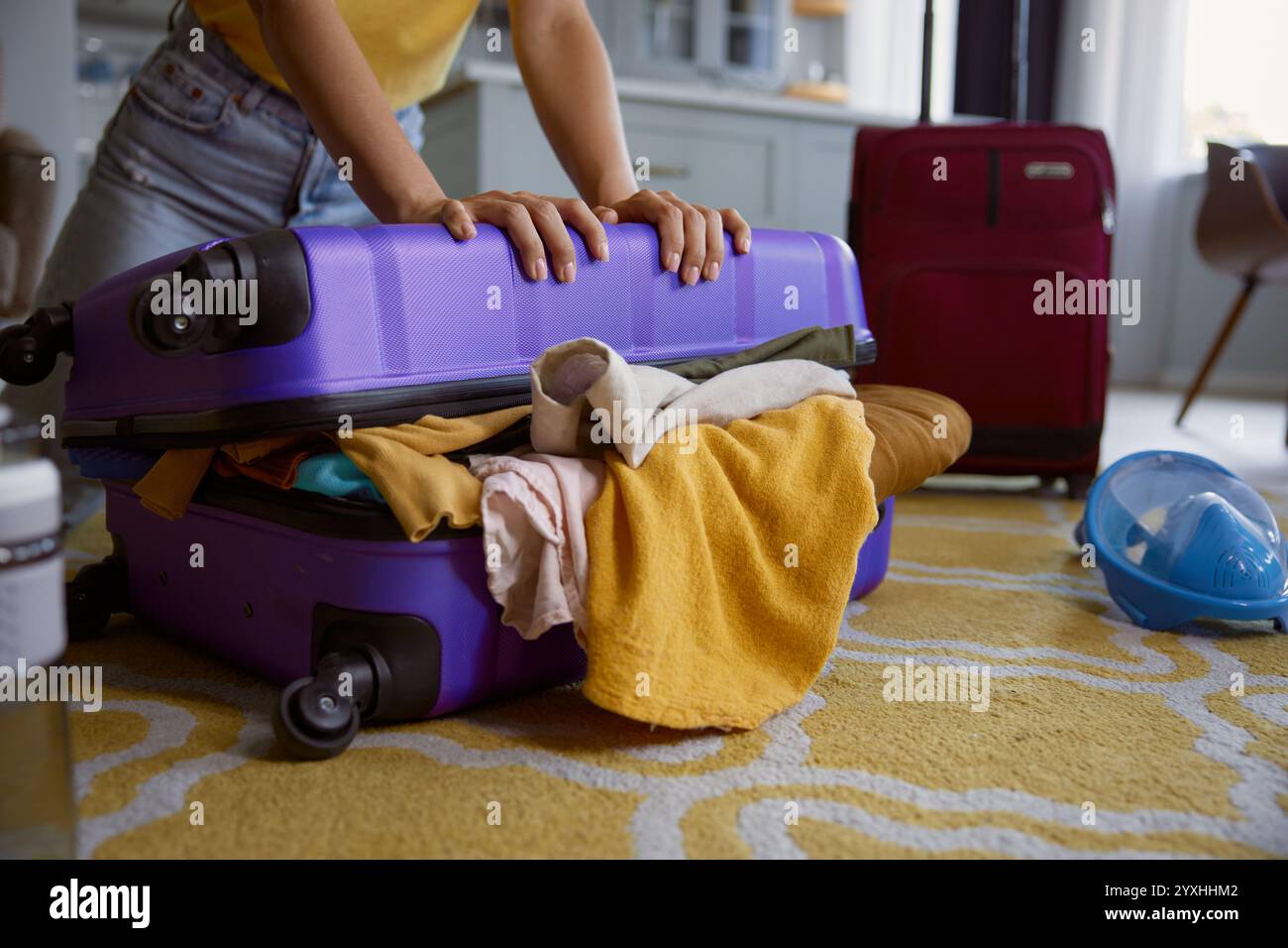Cute woman trying to close overloaded travel bag Stock Photo - Alamy