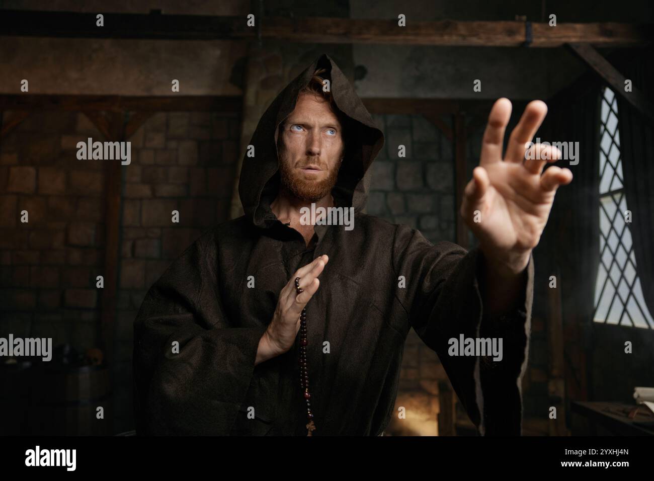 Portrait of friar wearing robe and golden cross reaching hand to camera ...