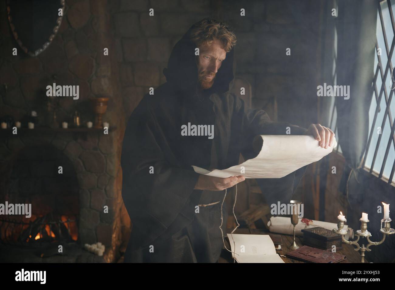 Mature medieval monk wearing robe with hood reading sacred manuscript ...