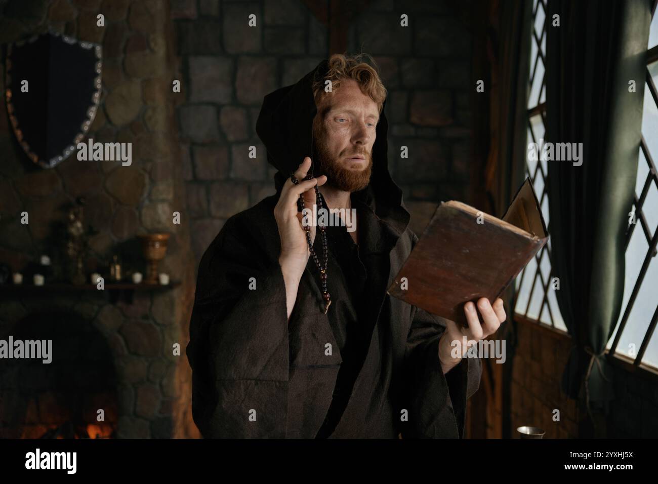 Medieval monk reading sacred religious book praying with rosary beads ...