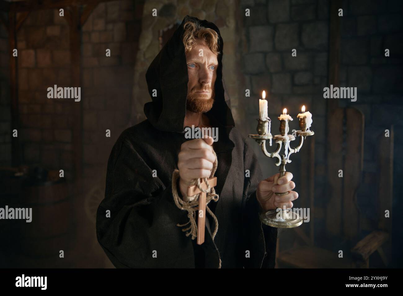 Portrait of hooded monk in medieval costume holding wooden cross and ...