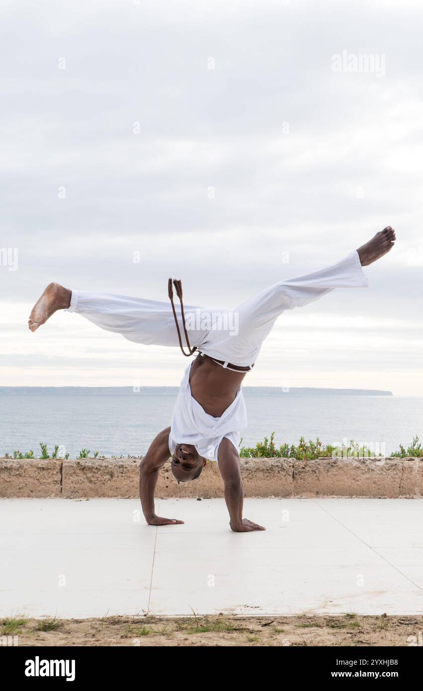 Capoeira martial artist in a handstand pose outdoors, expressing ...