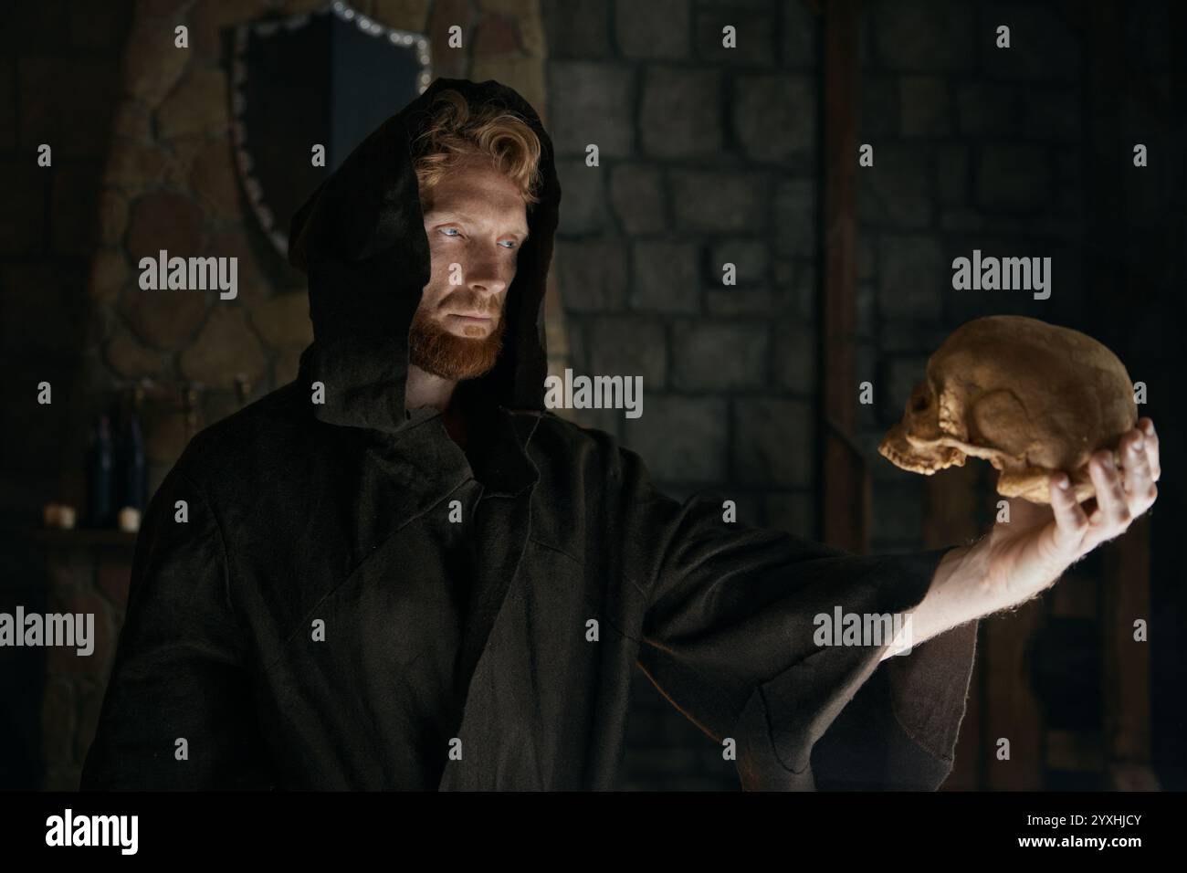 Serious medieval monk in hooded cloak looking at human skull Stock ...