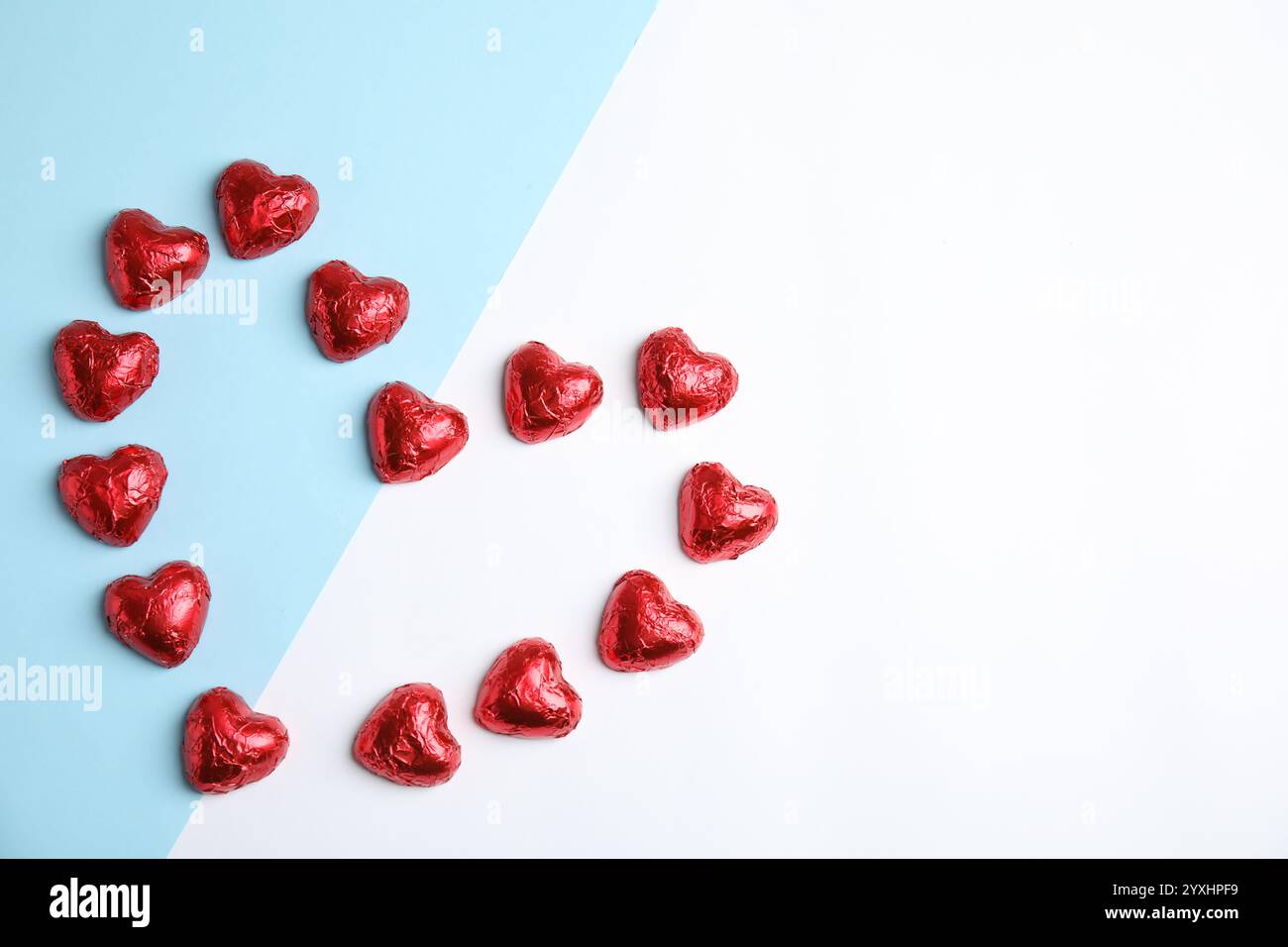 Heart of chocolate candies on color background, flat lay with space for ...