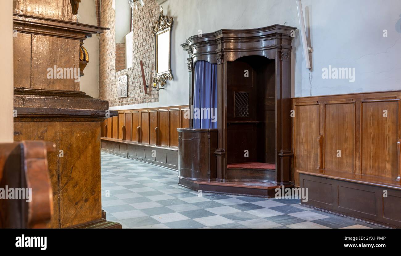 Lone empty wooden confession booth in traditional church interior ...