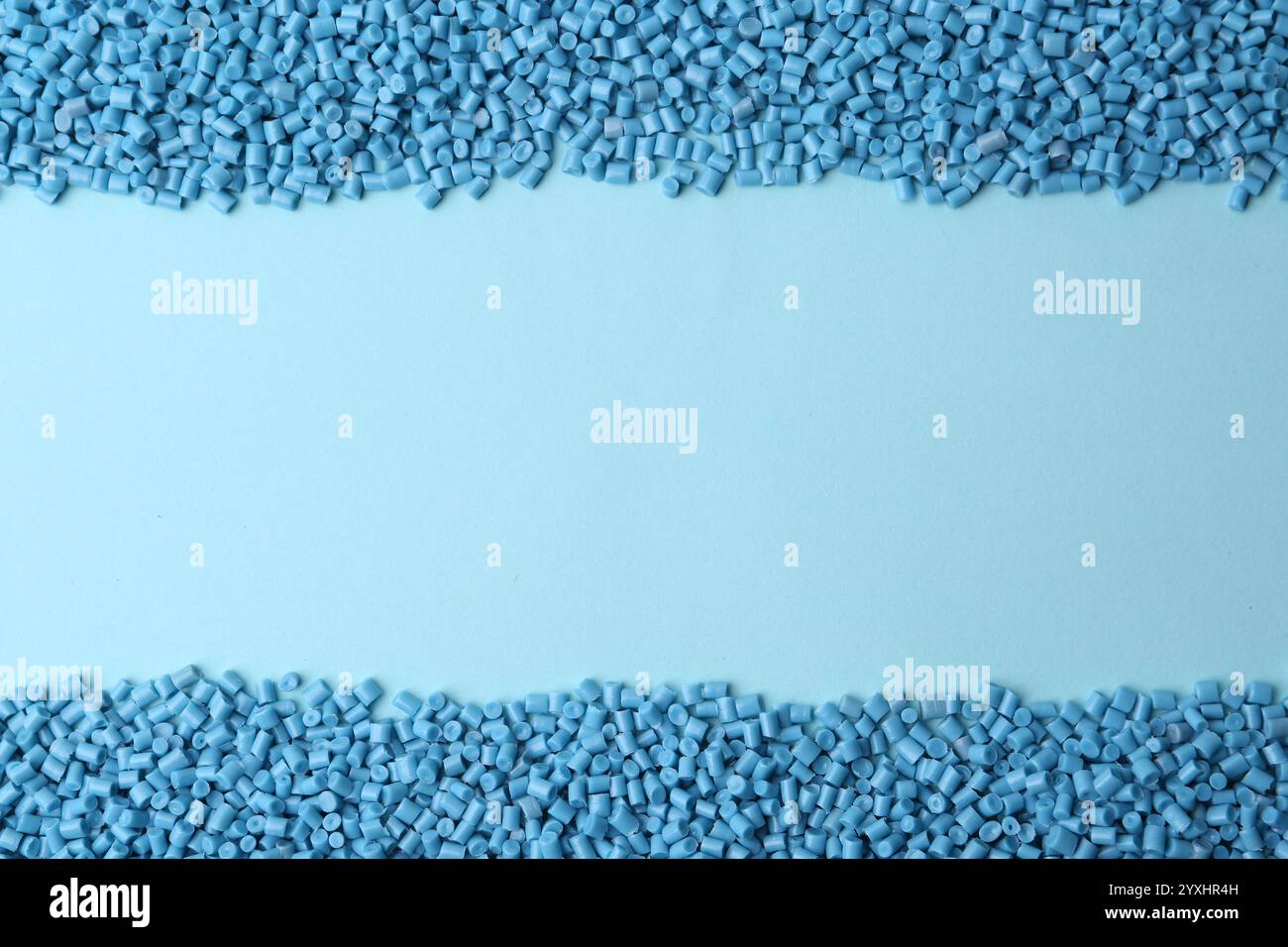 Pile of plastic granules on light blue background, top view. Space for ...