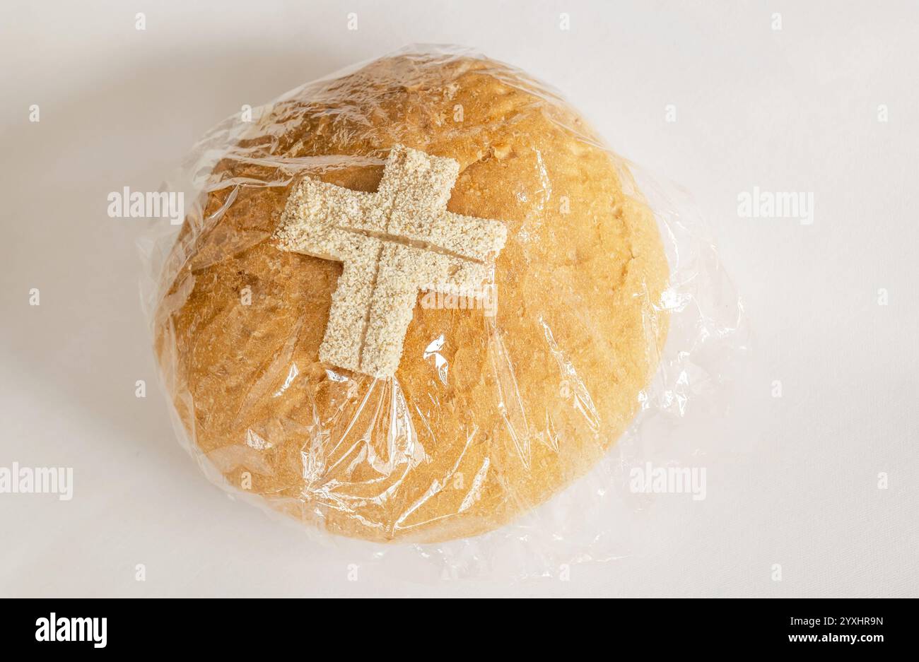 Fresh round bread loaf with Christian cross symbol on top wrapped in ...
