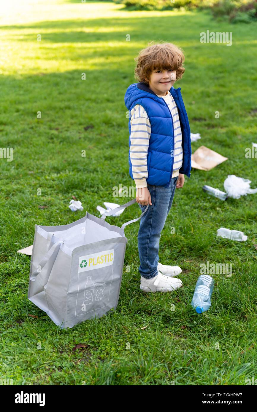 Small boy sorting garbage into recycle bags during community project ...