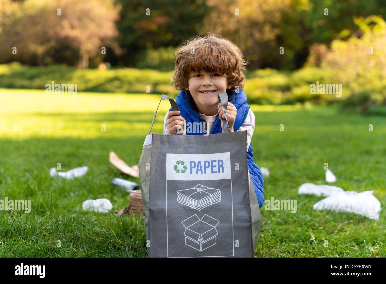 Little boy picking up paper garbage in park participating in social ...