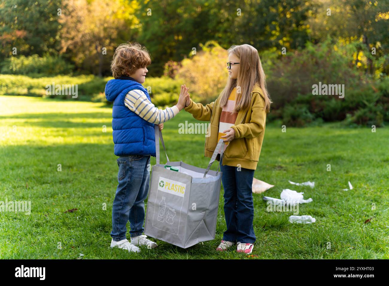 Boy and girl collecting garbage in park supporting environmental care ...