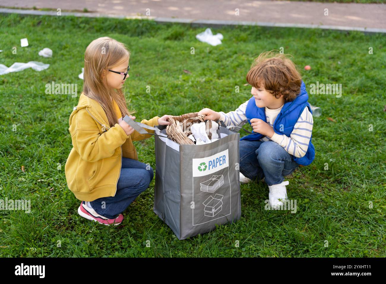 Boy and girl collecting paper garbage in park supporting environmental ...