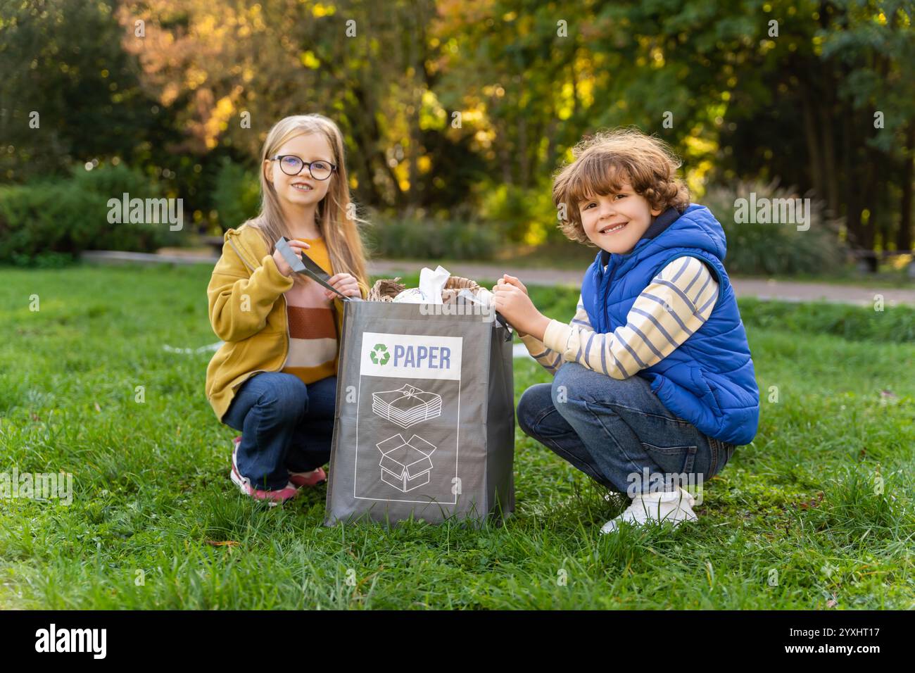 Little children picking up trash in park participating in a community ...
