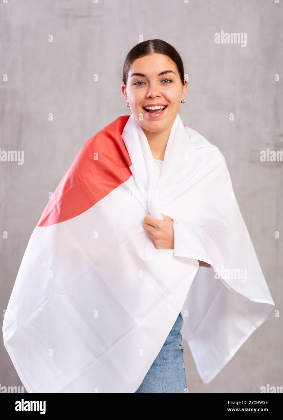 Joyous young woman holding Japan flag against unicoloured background ...