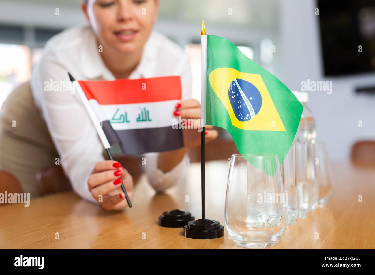 Female secretary places flags of the Iraq and Brazil flag on table ...