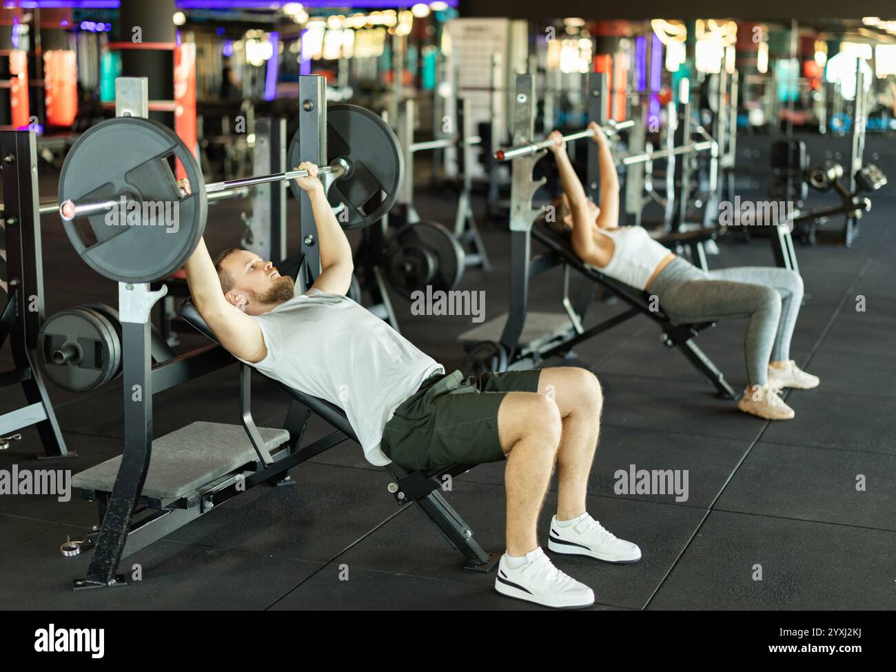 Guy lies on bench and lifts barbell, strengthens muscles of upper body ...