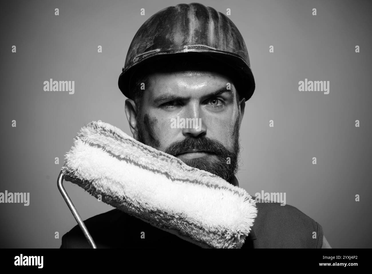 Serious house painter with roller for painting walls. Male painter in ...