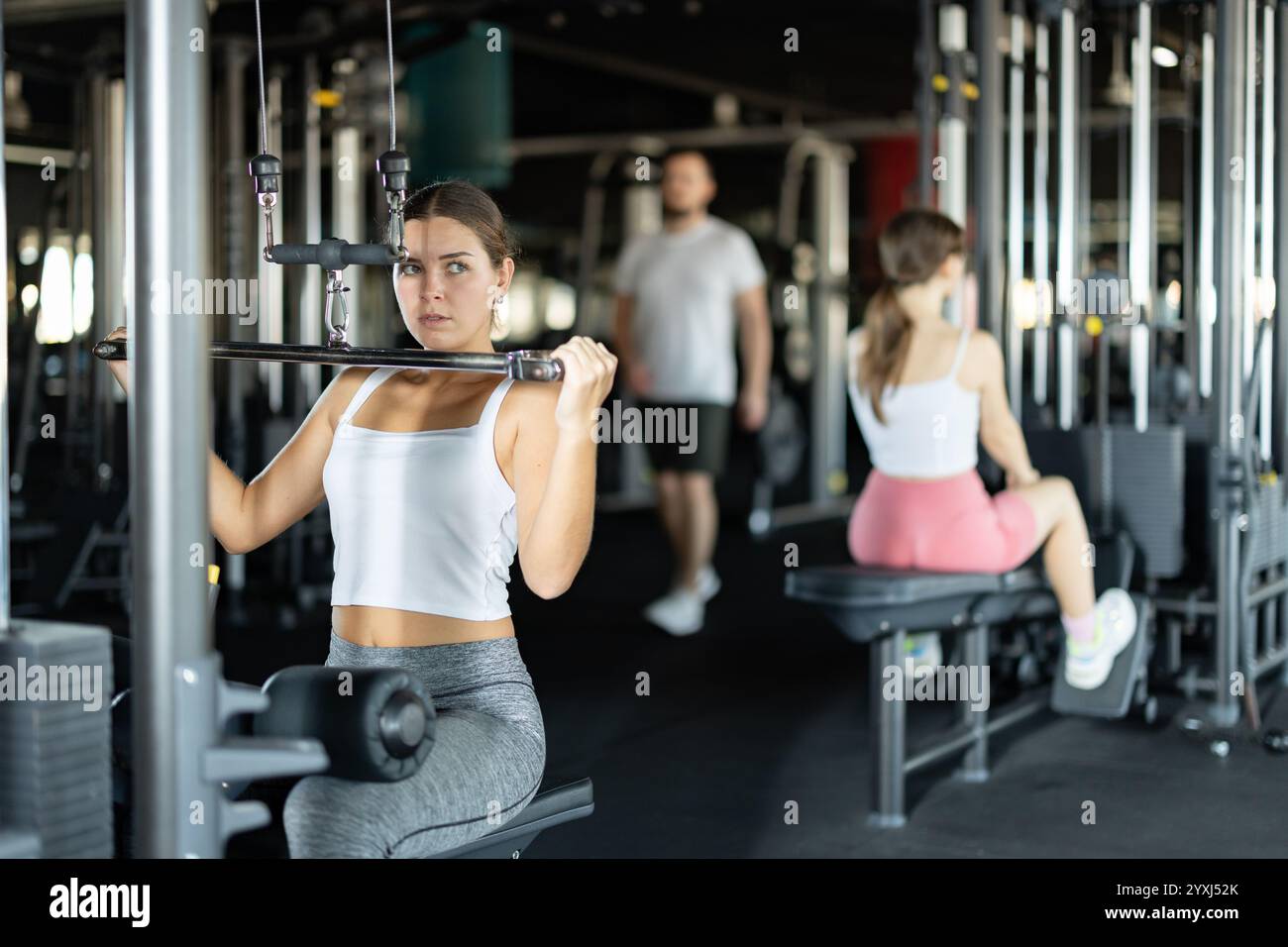 Slender athletic woman work out muscles of hands on cable crossover ...