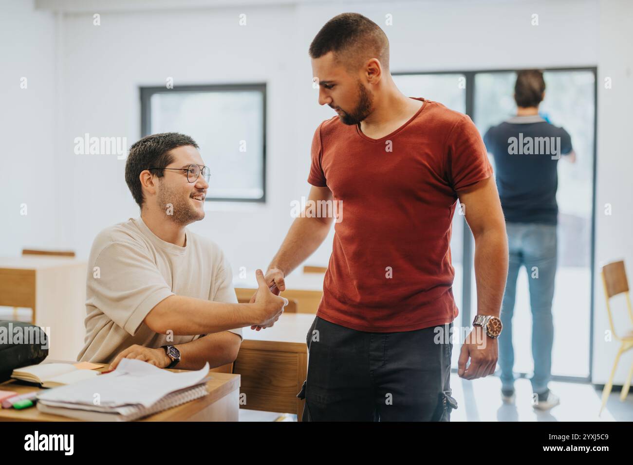 Two students shaking hands in a bright classroom setting Stock Photo ...
