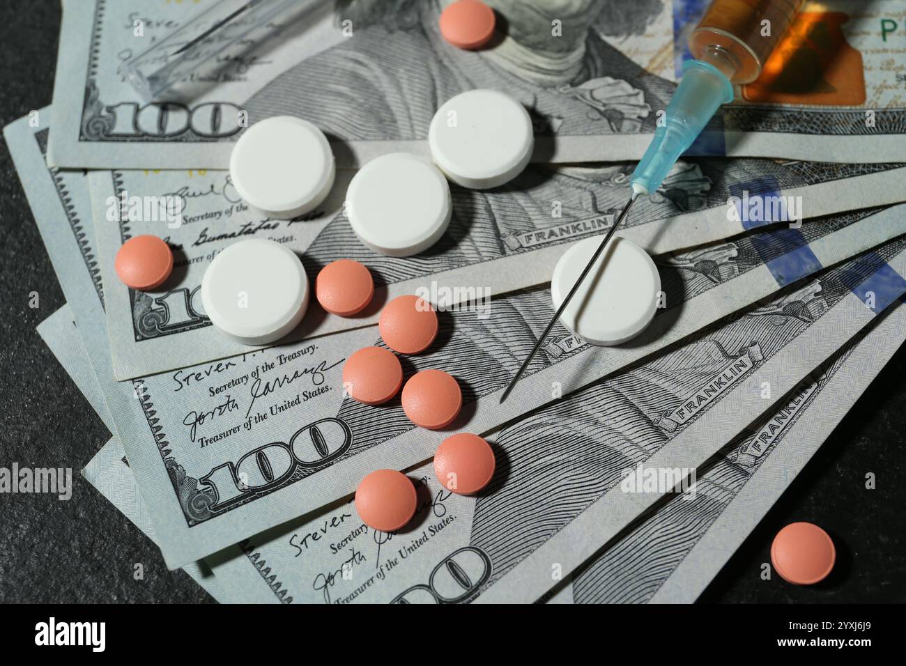 Drug addiction. Dollar banknotes, pills and syringe on gray table ...