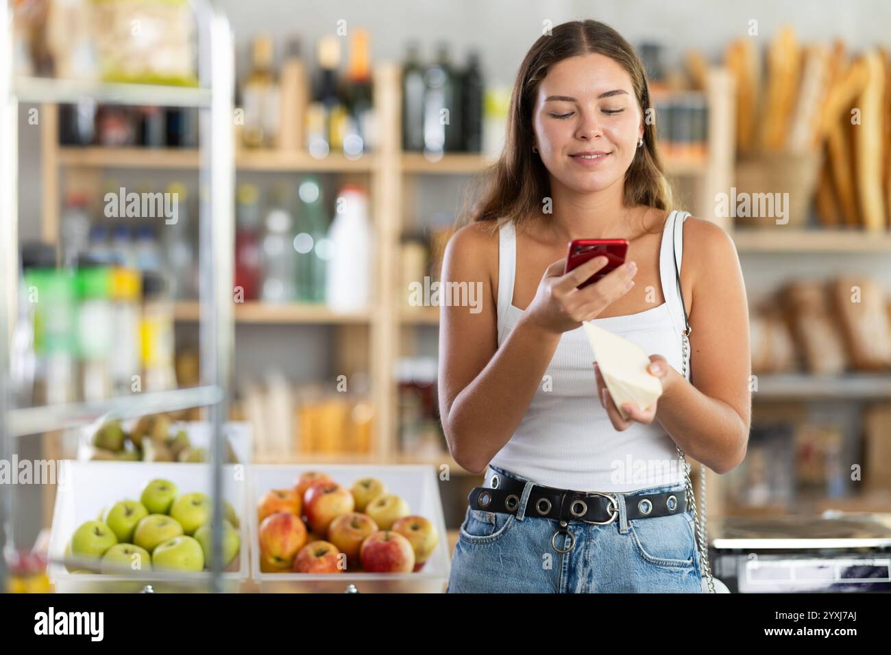 Female shopper scans QR code on cheese label using smartphone. Checking ...