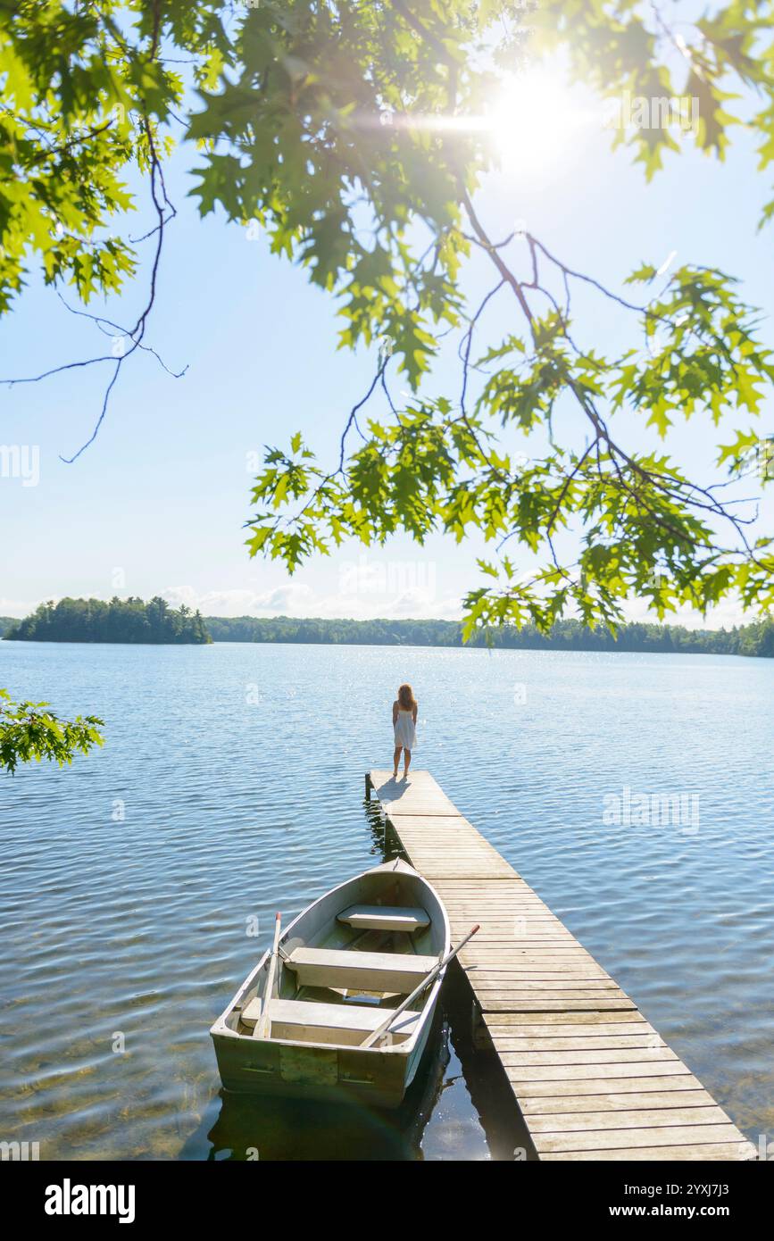 Rear view of adult woman standing at end of dock Stock Photo - Alamy