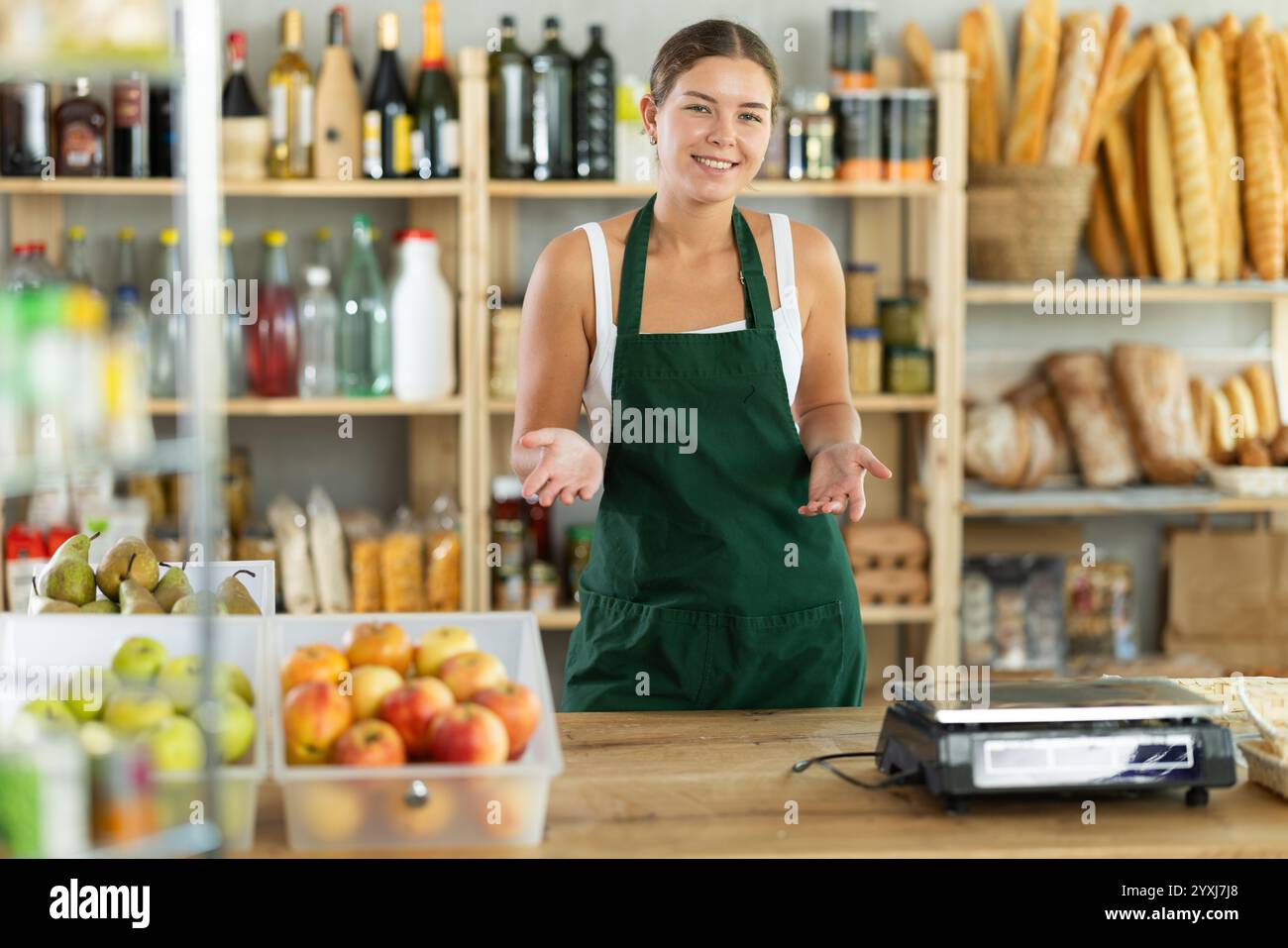 Portrait of smiling female salesperson in apron behind supermarket ...
