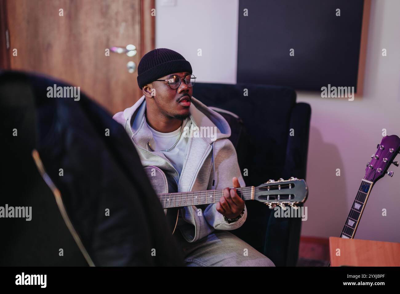 Young musician playing guitar in a cozy recording studio Stock Photo ...