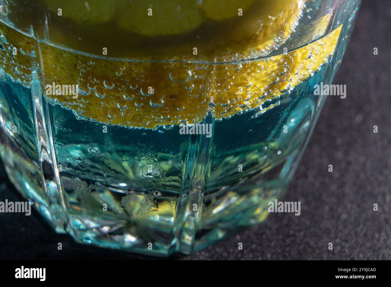 Glass cup with blue transparent liquid, lemon slice and some air ...