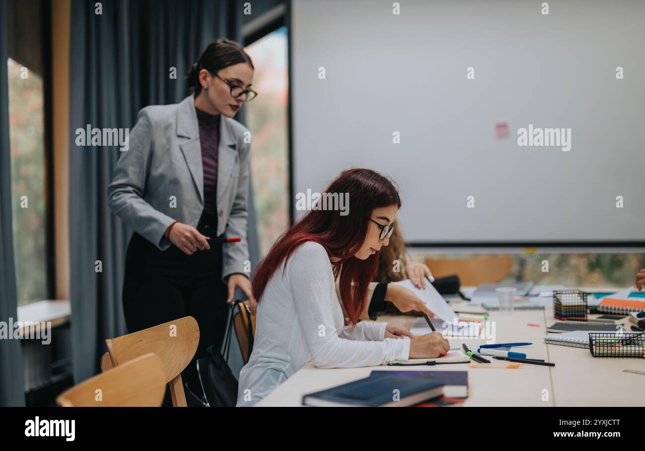Teacher assisting student with notes in modern classroom setting Stock ...