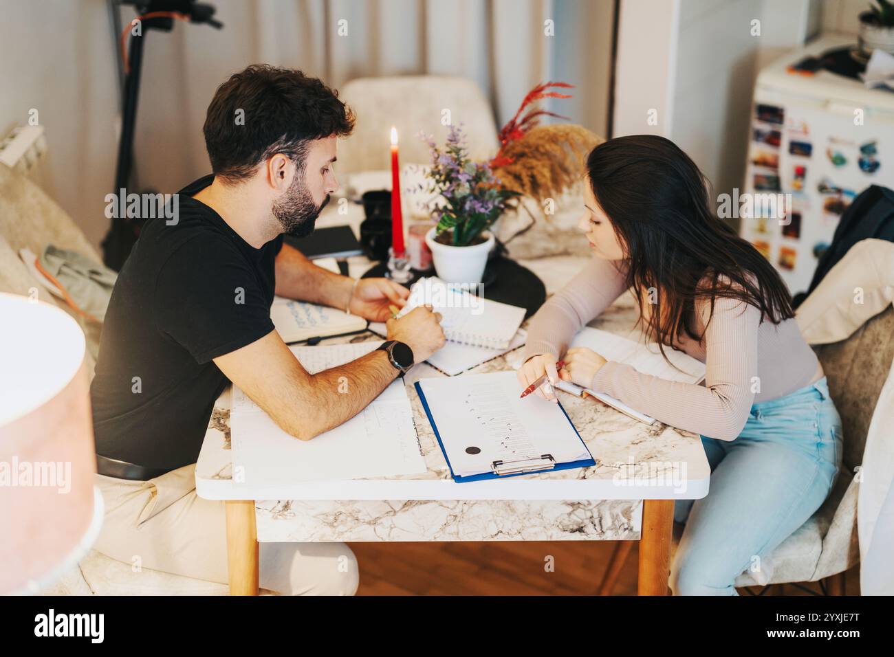 Focused college students studying at home together at a cozy table ...