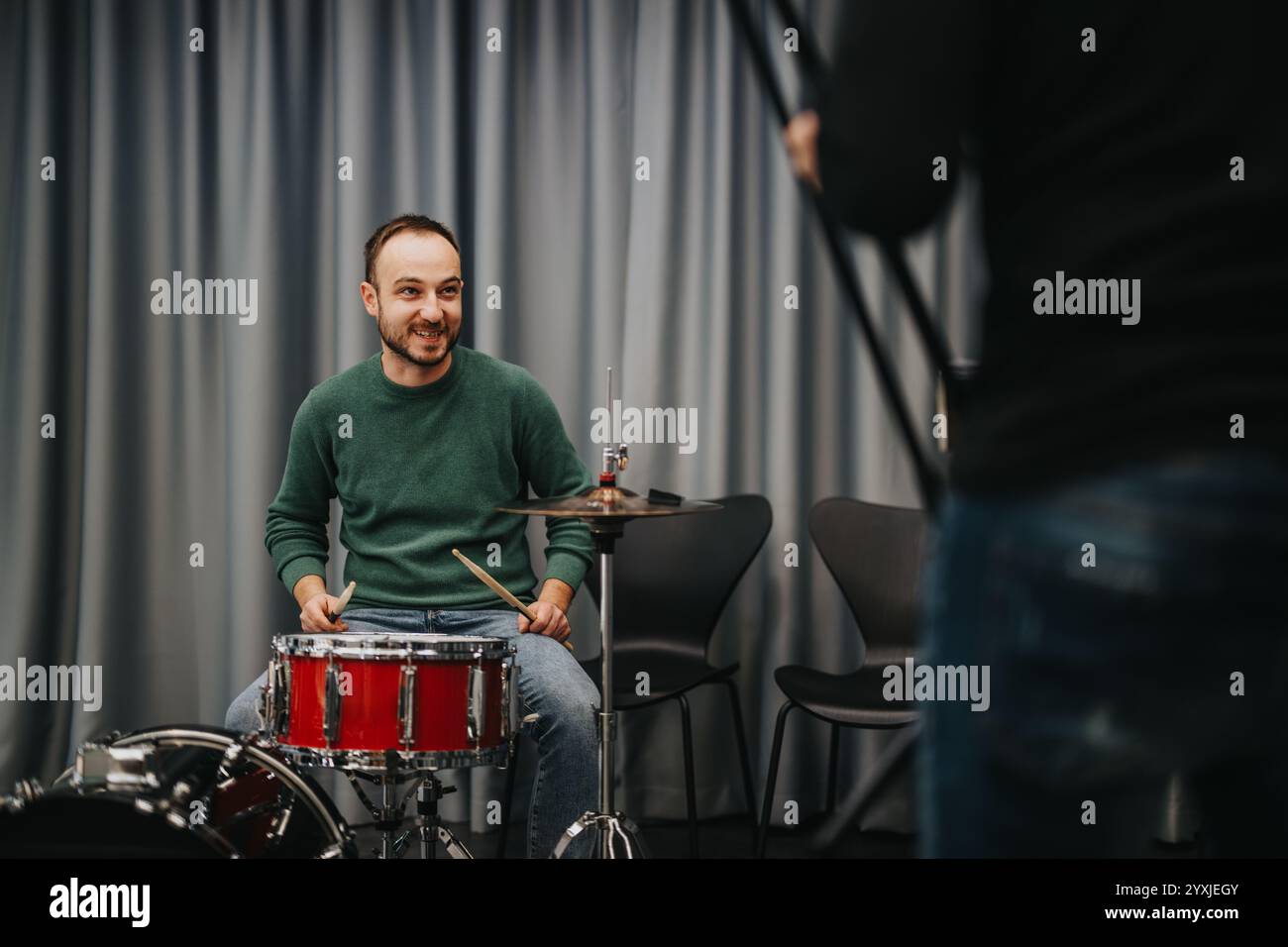 Smiling drummer practicing in a music studio with red drum set Stock ...