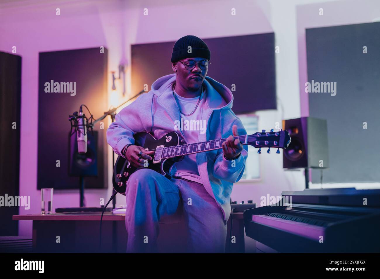 Musician playing electric guitar in professional recording studio with ...