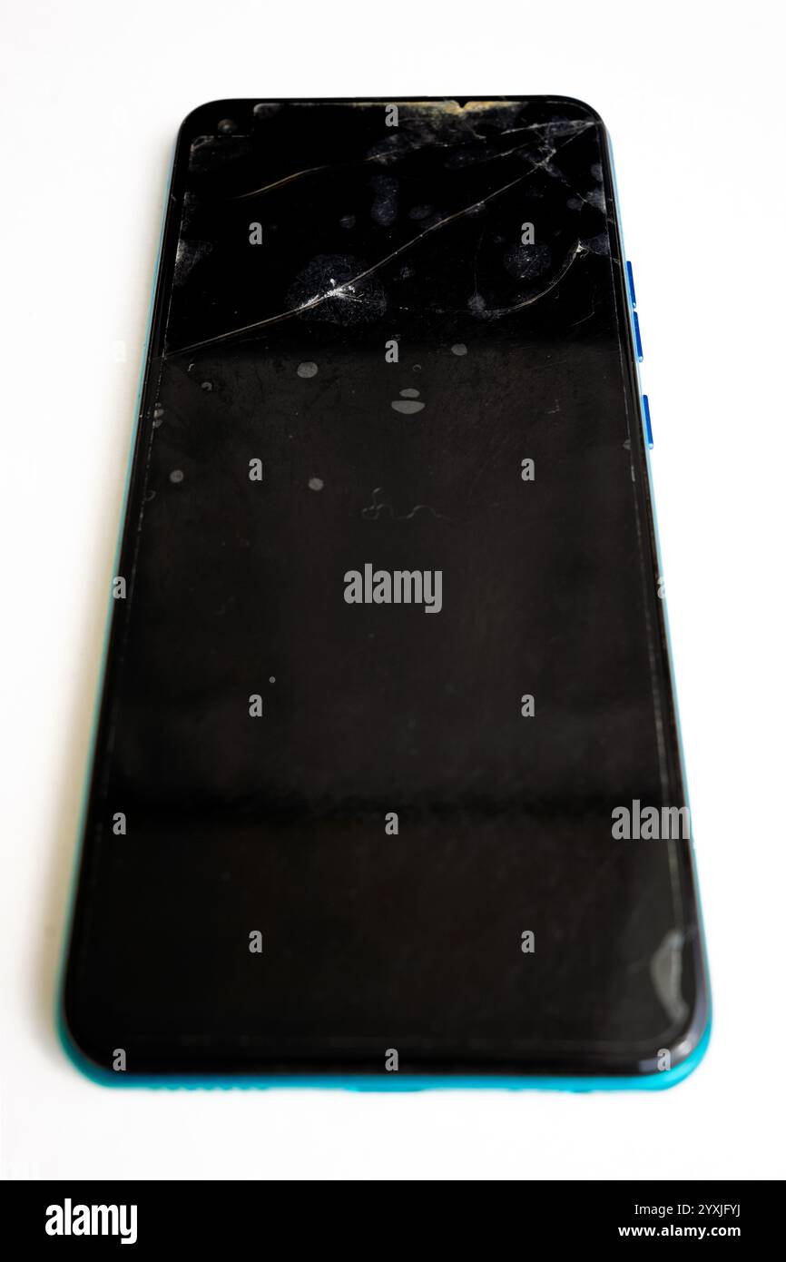 A damaged smartphone rests on a white surface, showcasing a cracked ...