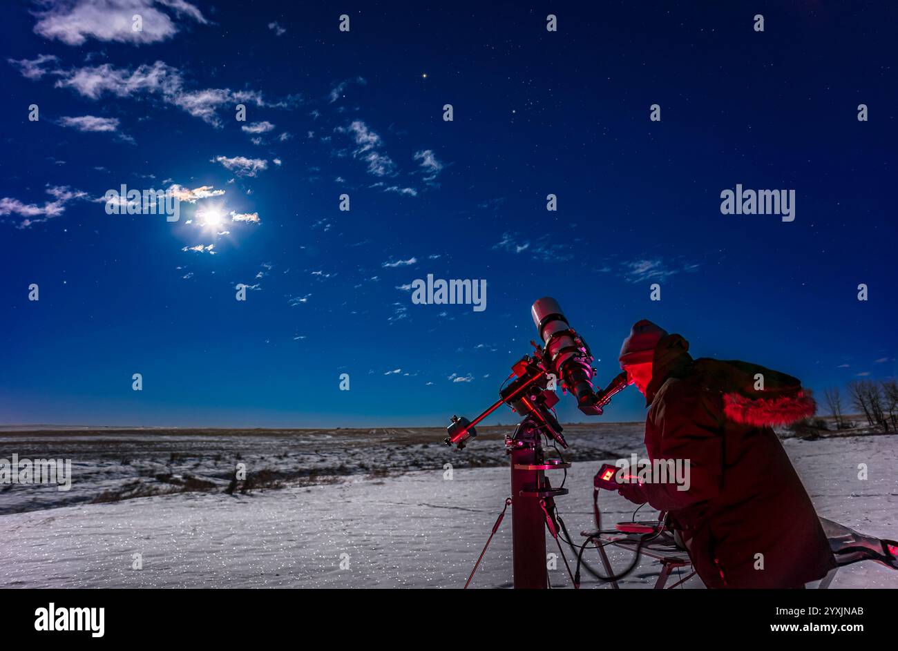 Astronomer observing Mars through a telescope on a mild winter night in ...