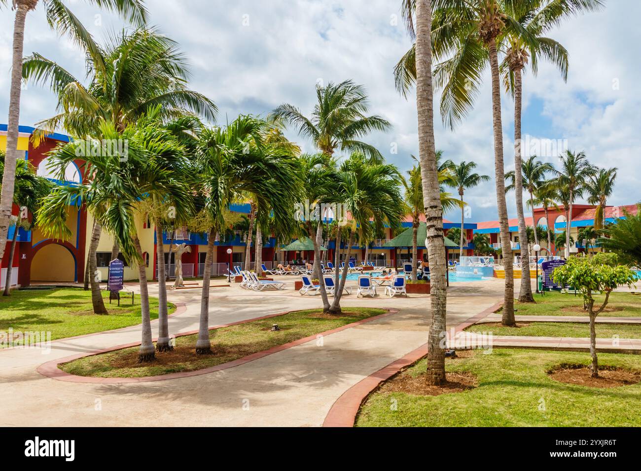 A tropical resort with palm trees and a pool. The resort is full of ...