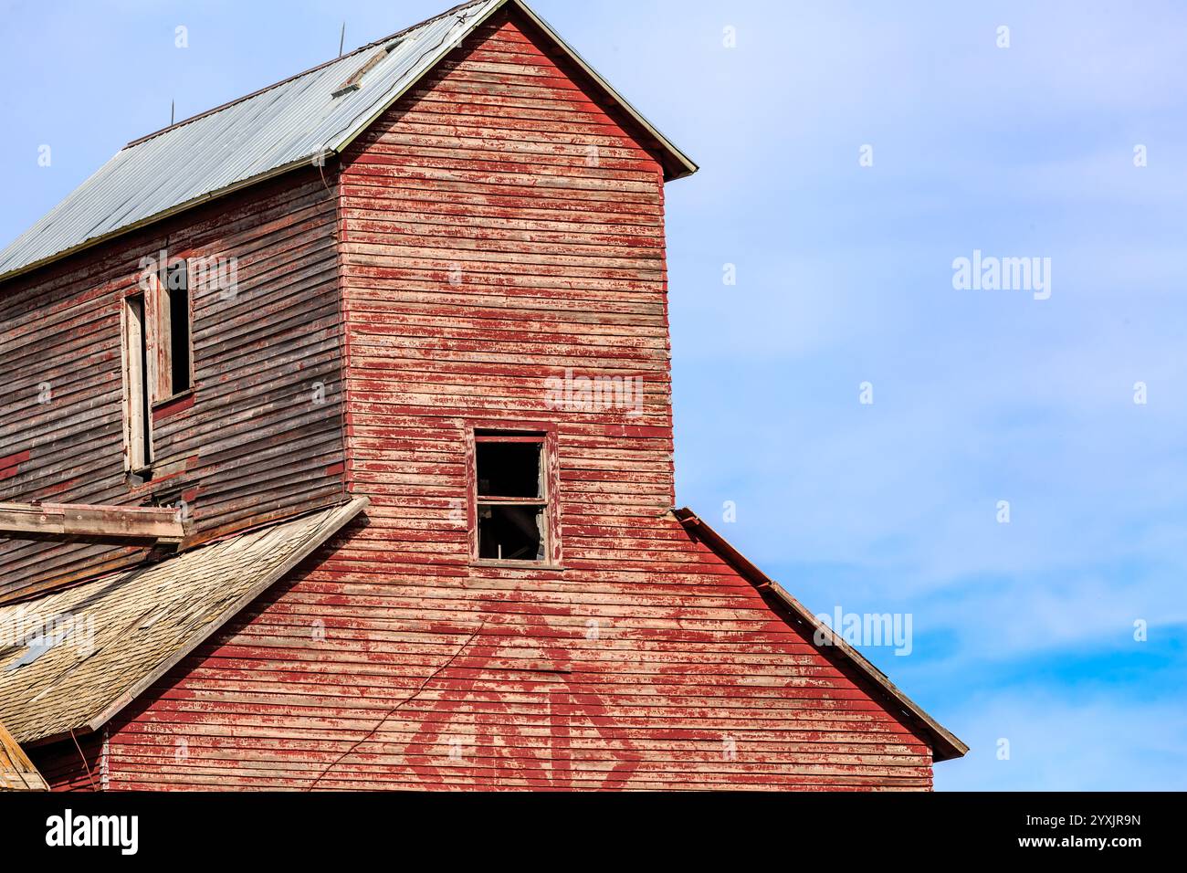 A red barn with a slanted roof and a window. The barn is old and has a ...
