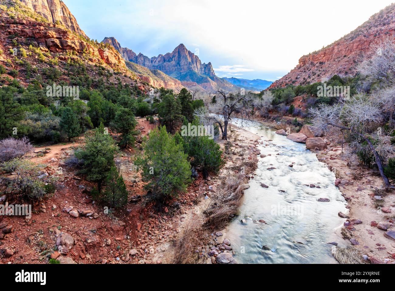 A river runs through a canyon with trees on either side. The water is ...