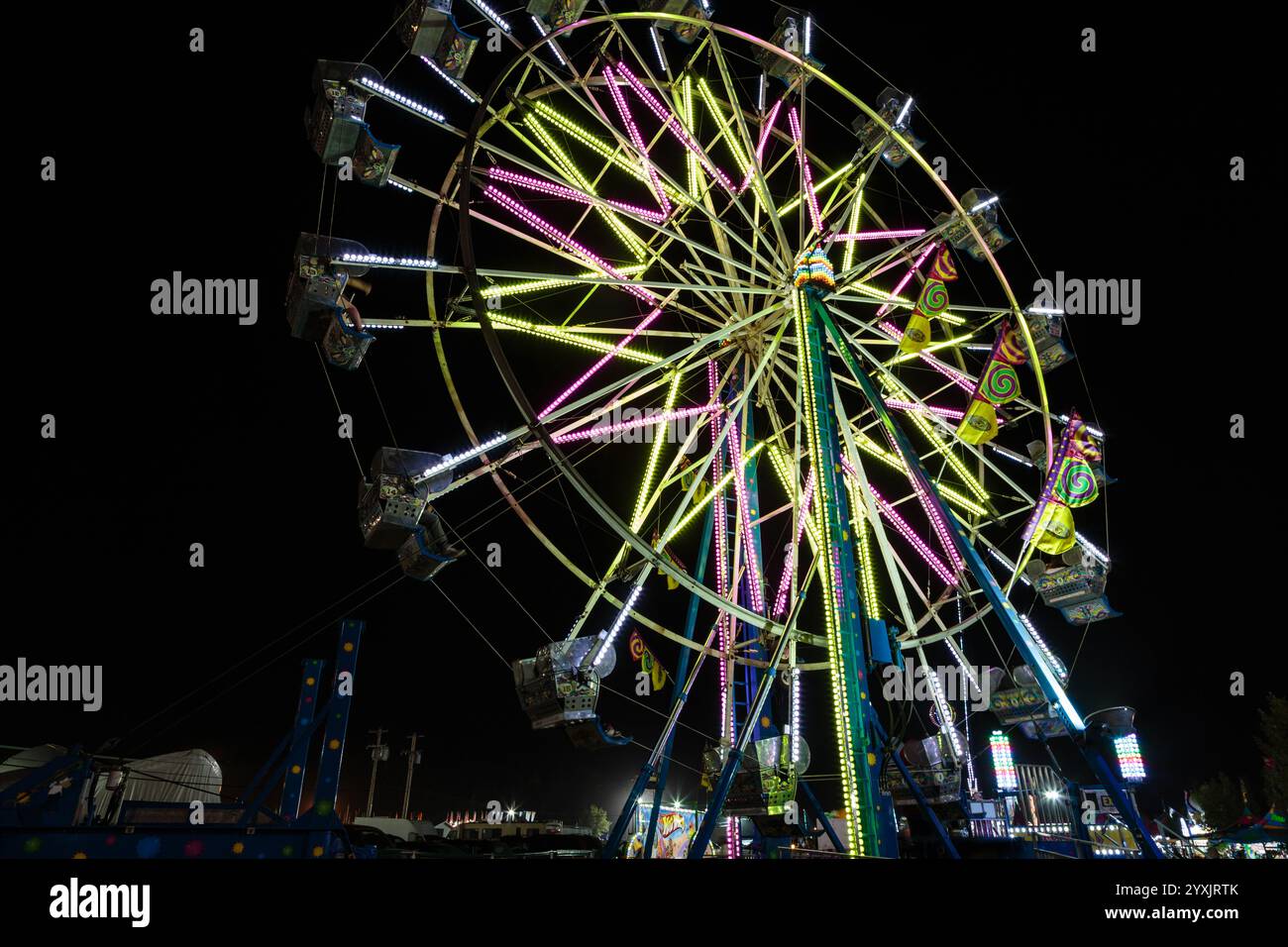 A colorful merry go round with neon lights is spinning in the dark. The ...