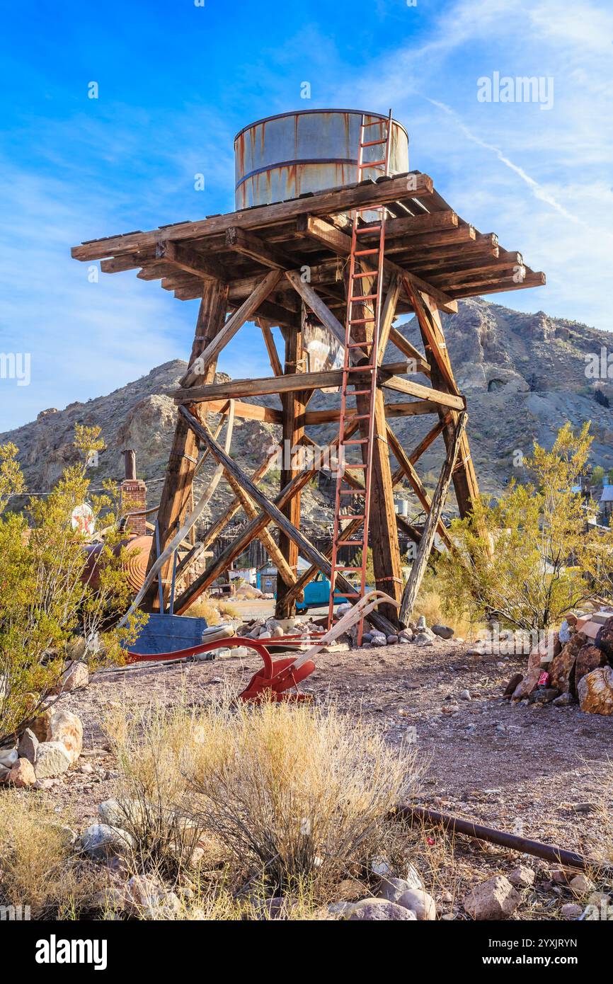 A rusty water tower sits in the desert. The tower is surrounded by dry ...