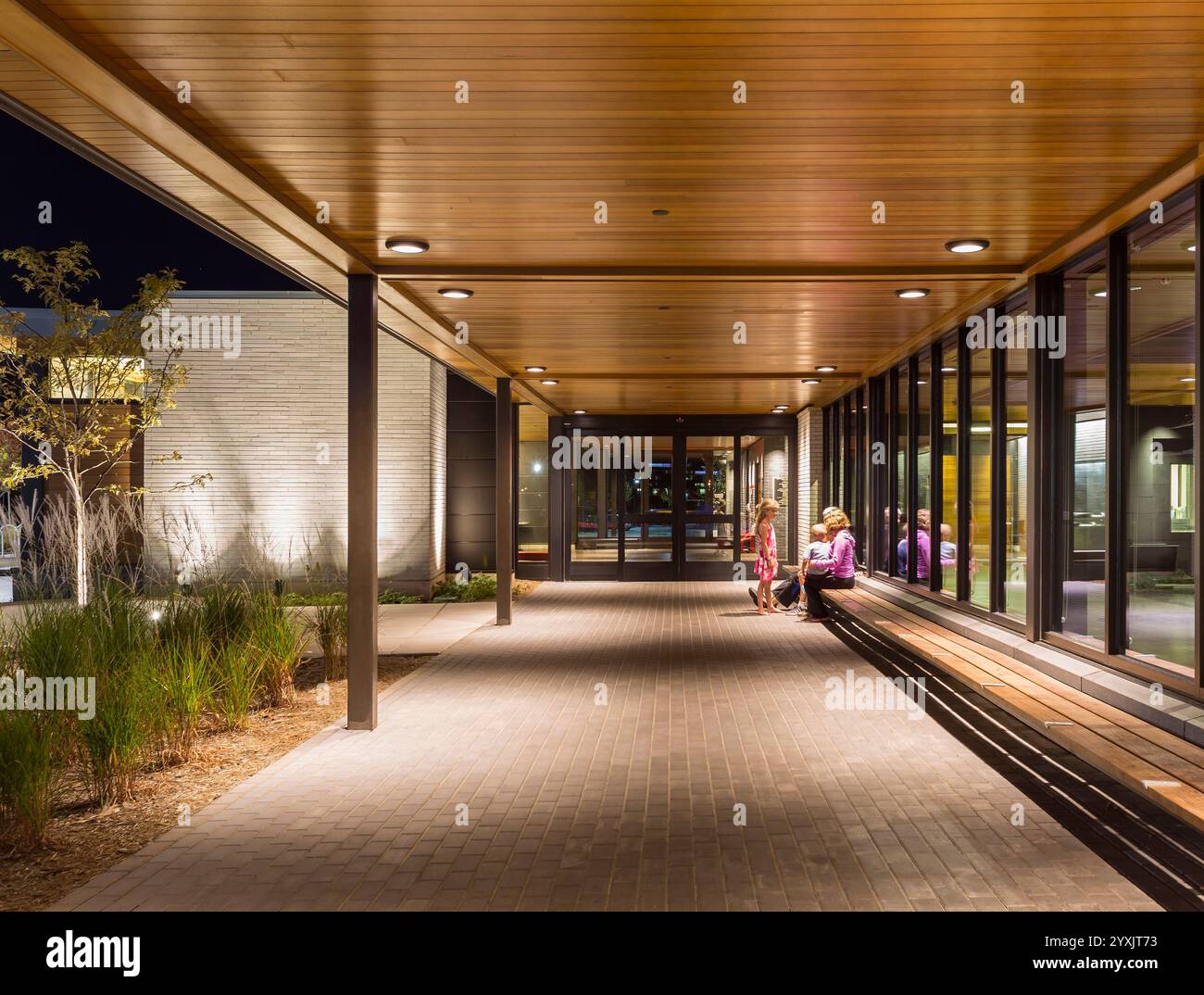 Entrance to new modern park building at night showing brick walkway ...