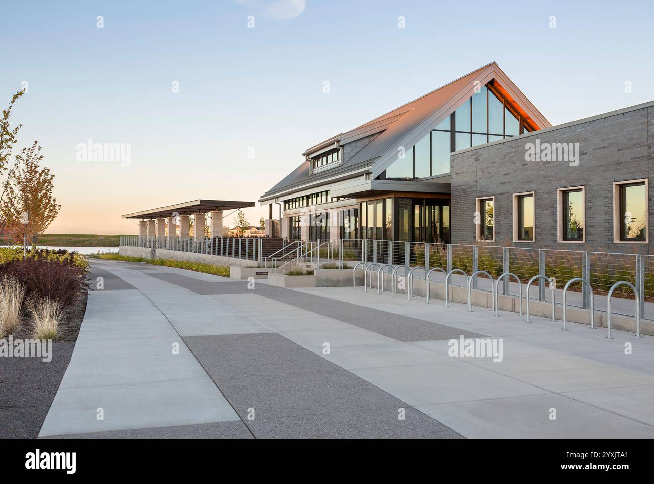Wide sidewalk leading up to modern park building with lots of windows ...