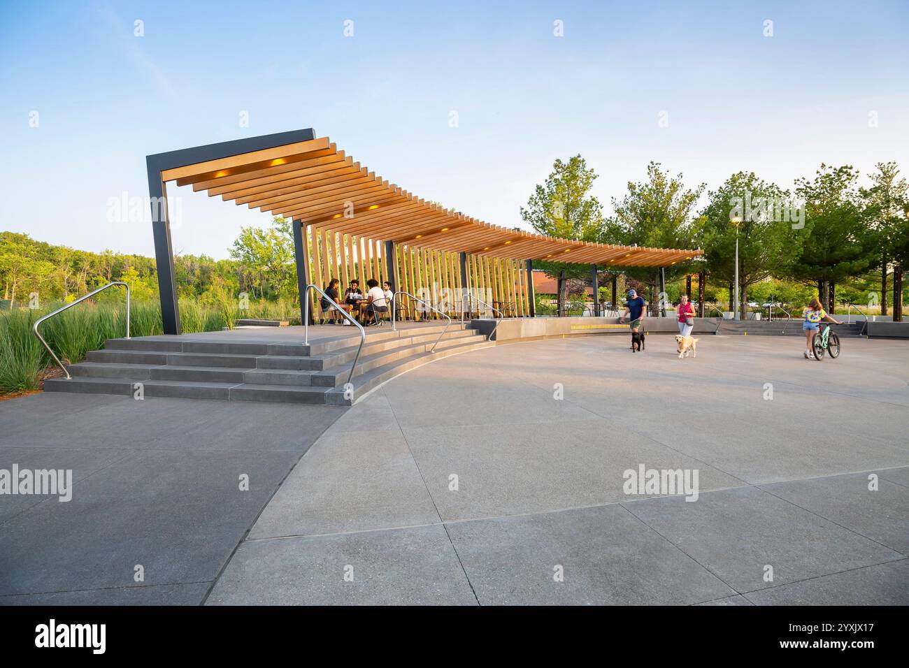 People enjoying a park pavilion made from steel and wood slats next to ...