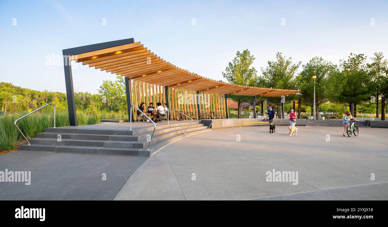 People enjoying a park pavilion made from steel and wood slats next to ...