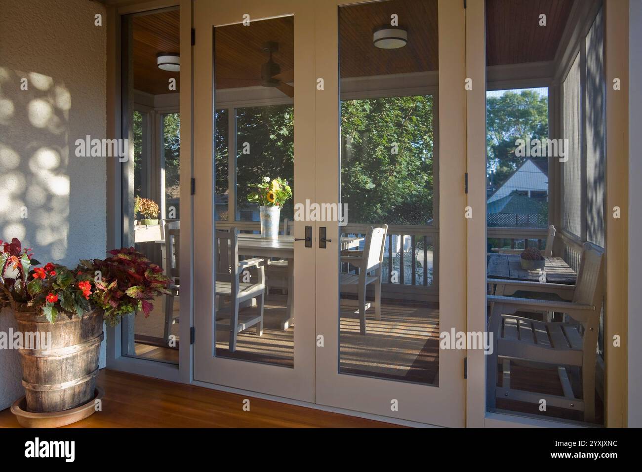 Sunlight streams into screened porch with table and chairs Stock Photo ...