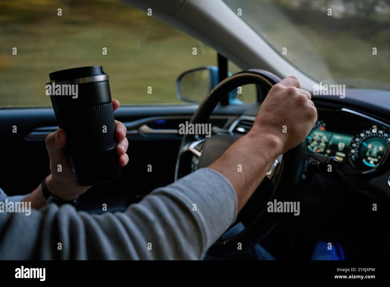 Person drives car on highway road and holding travel mug with hot ...
