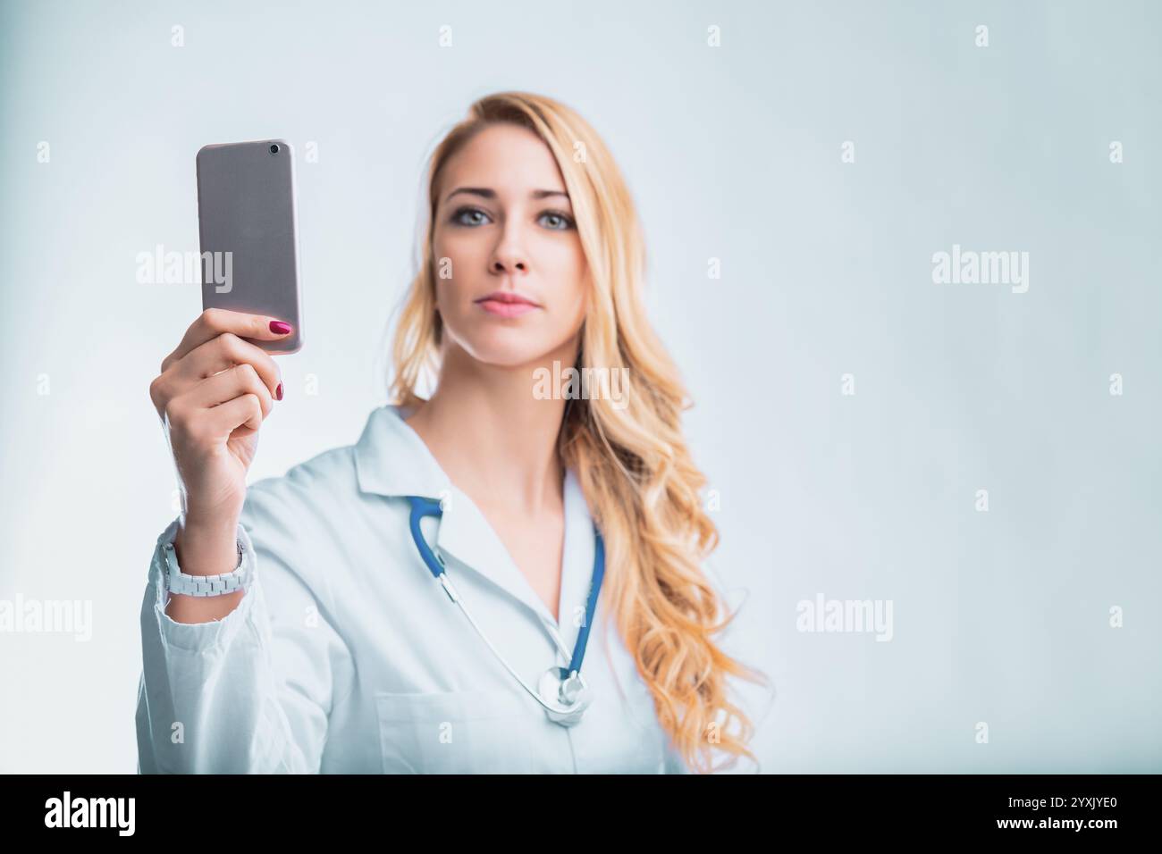 Young female doctor using a smartphone app for remote patient ...