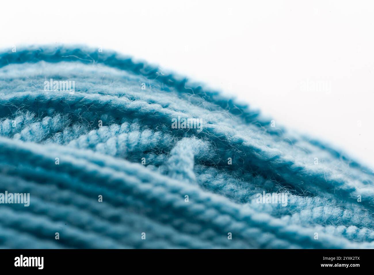 A blue ball of yarn with a white background. The yarn is knitted and ...