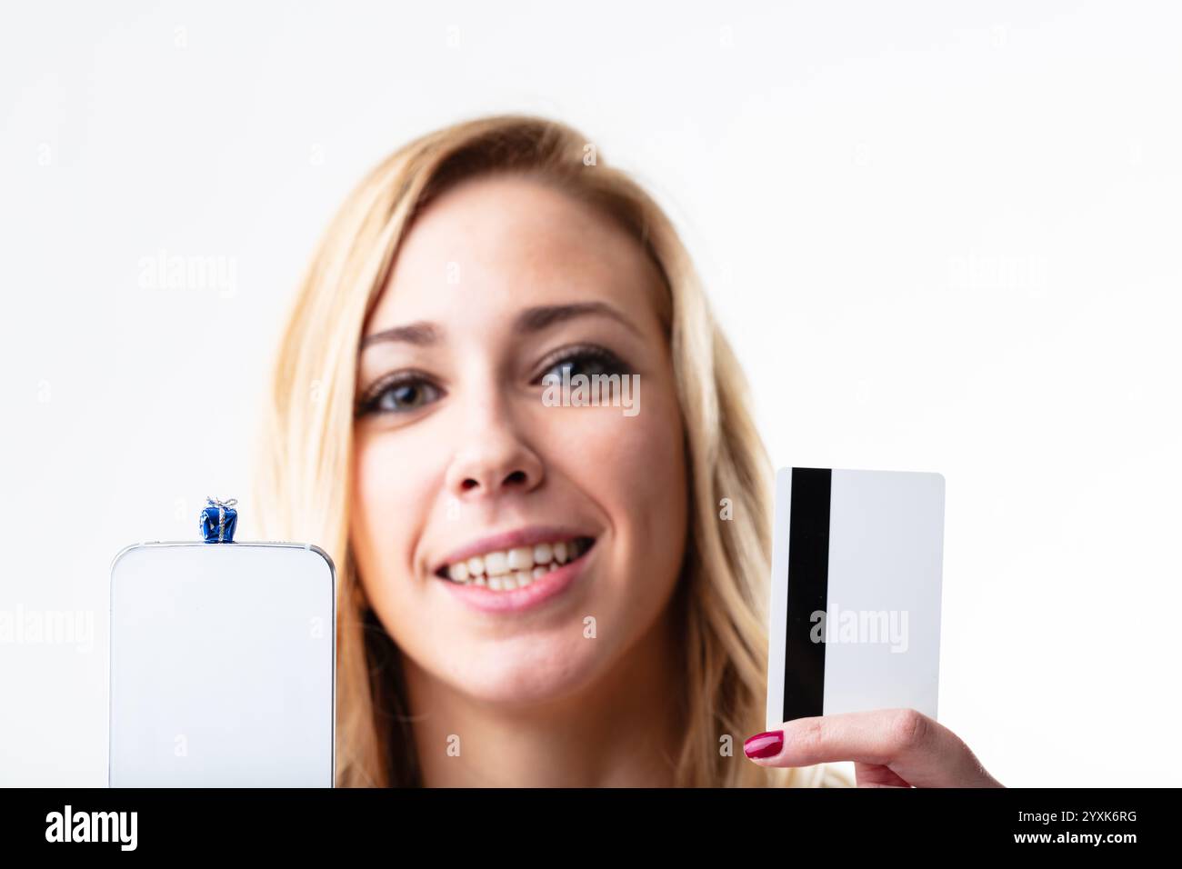 Happy blonde woman with smartphone, credit card for quick online shopping. Convenience in the ...