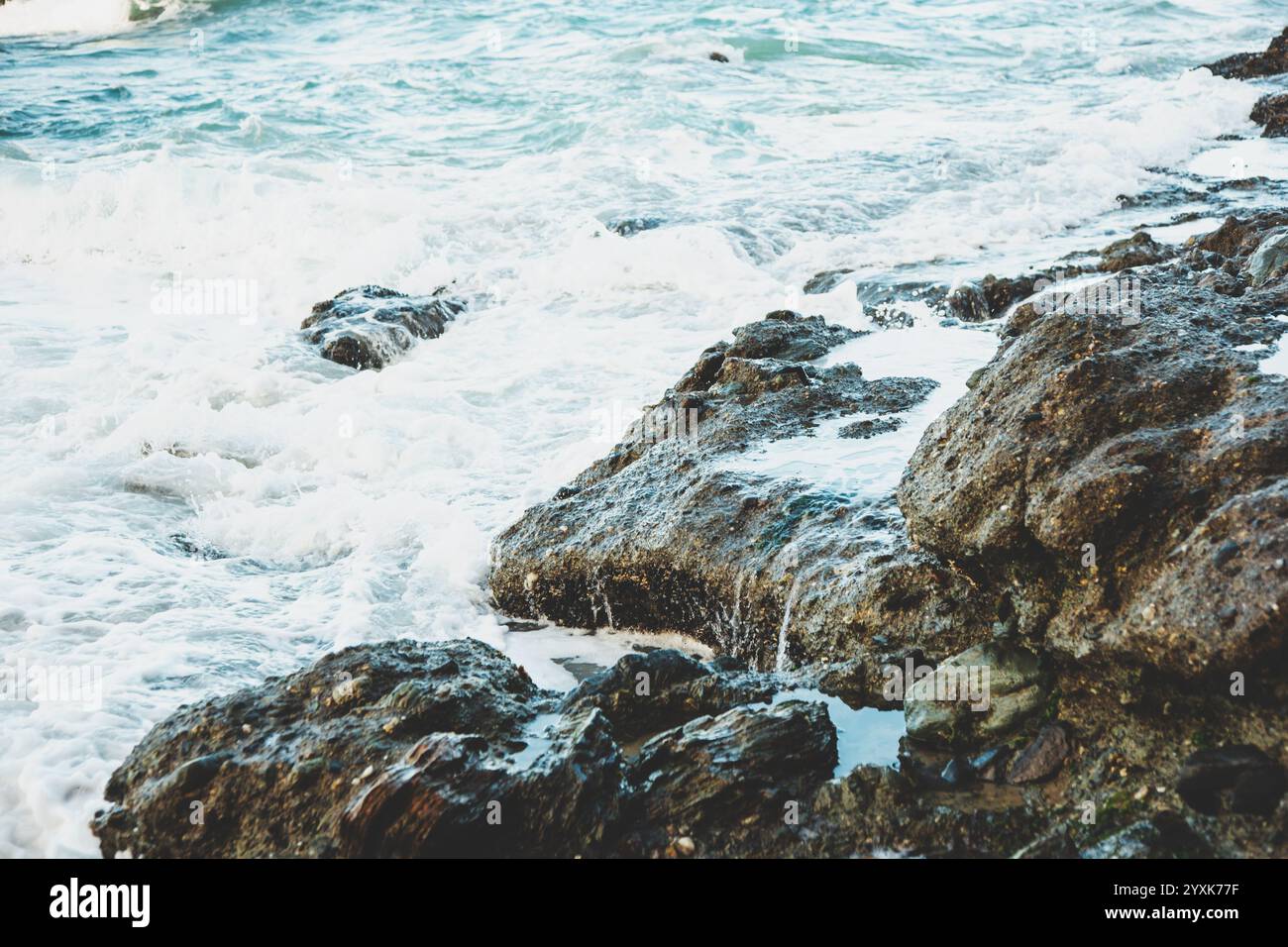 A view of a rocky beach landscape with falling ocean water and sharp ...