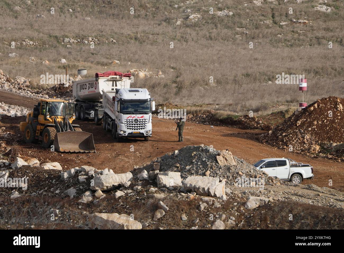 An Israeli soldier stands next to trucks inside the buffer zone near ...